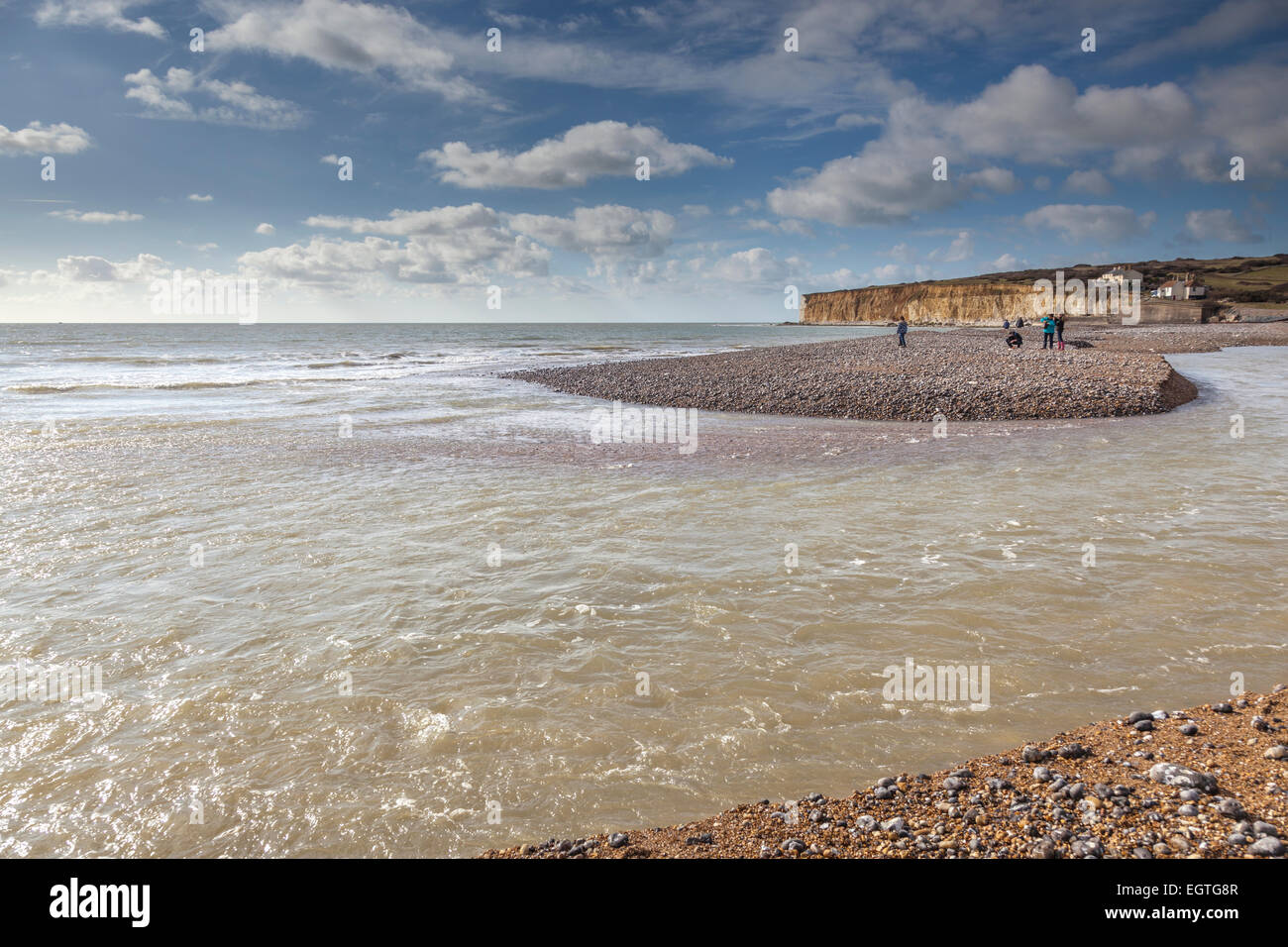 The estuary of the River Cuckmere flowing into the sea at high tide ...