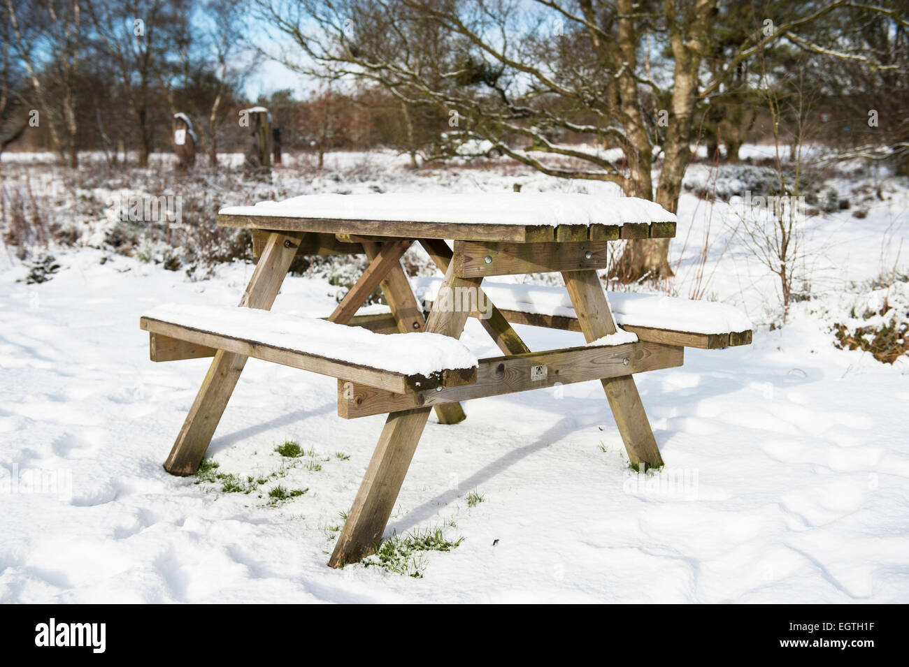 Snow covered picnic bench in rural countryside woodland setting Stock ...