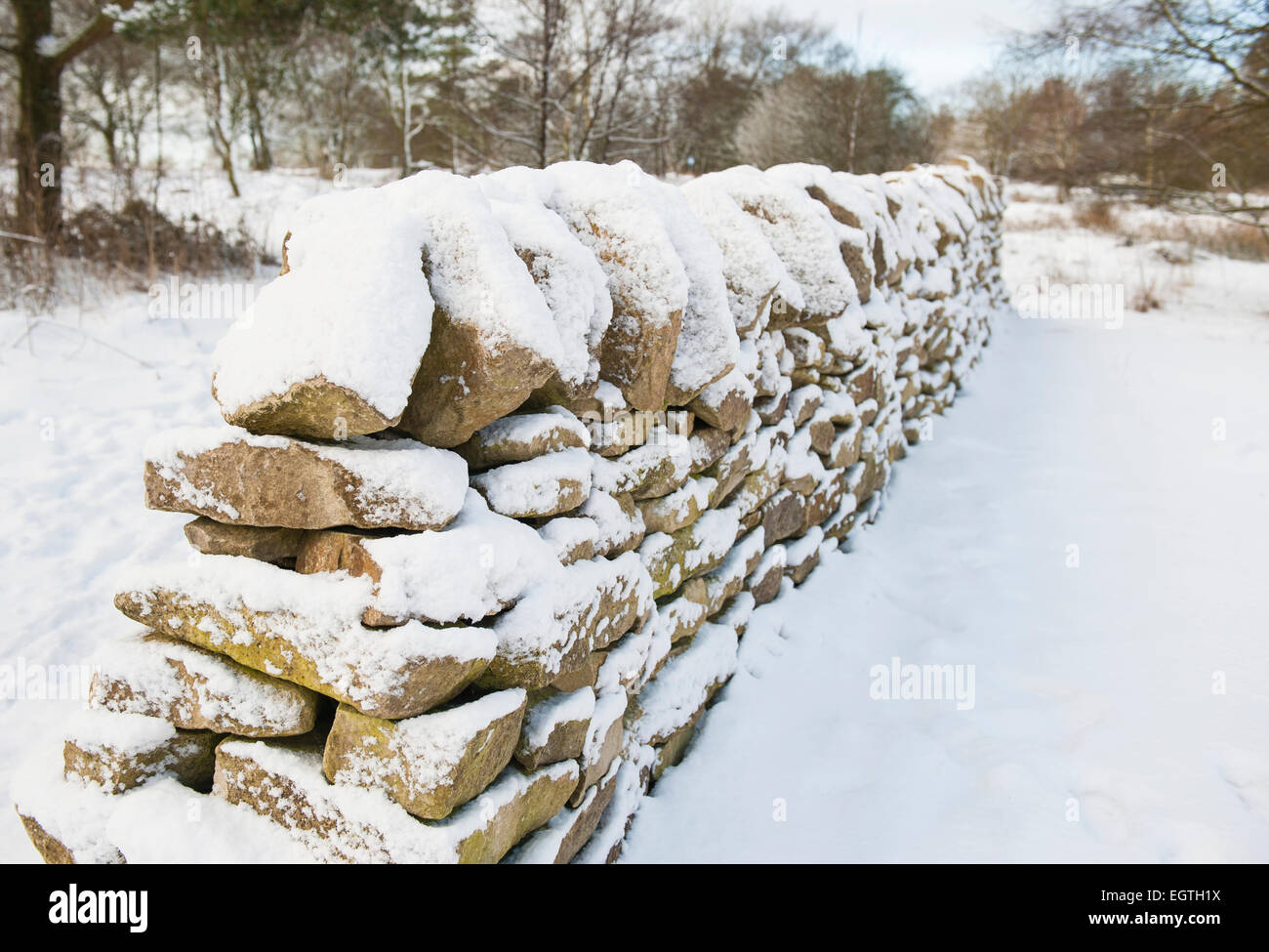 Snow covered dry stone wall in an english winter countryside rural ...