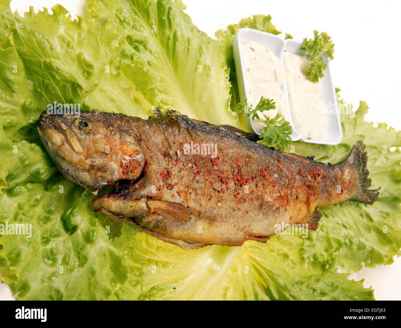 Fried fish with herbs and spices against white Stock Photo - Alamy