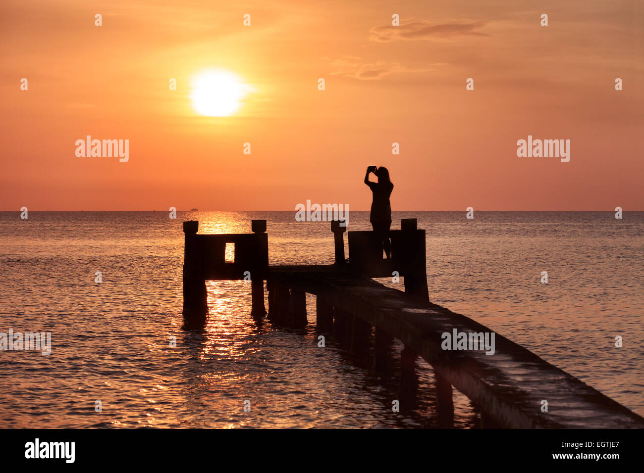 Sunset on a pier in the ocean Stock Photo - Alamy