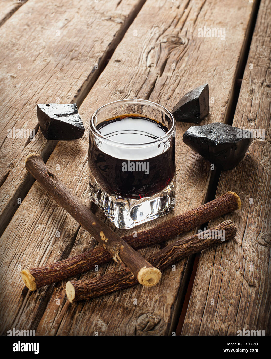 Licorice liqueur with pure blocks and roots on wooden table Stock Photo ...