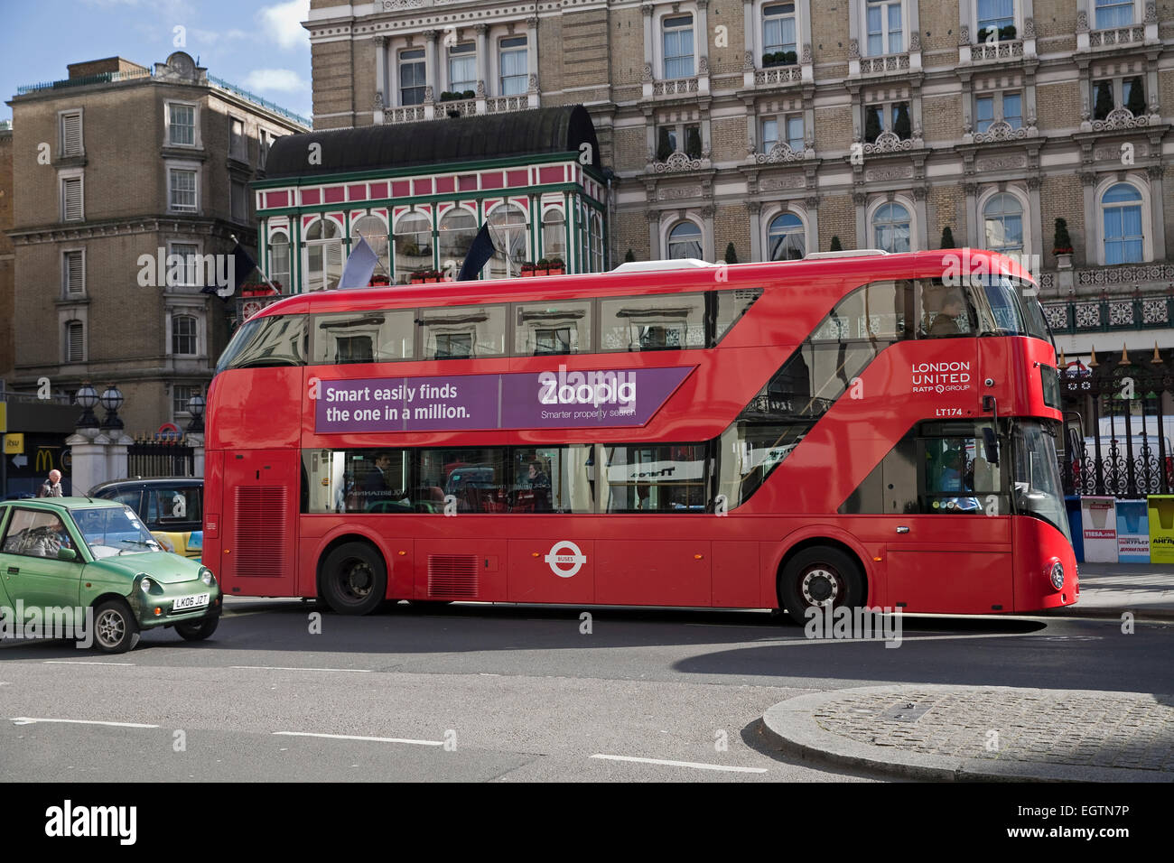 A new shape red London Bus stops outisde the Amba hotel in the Strand ...
