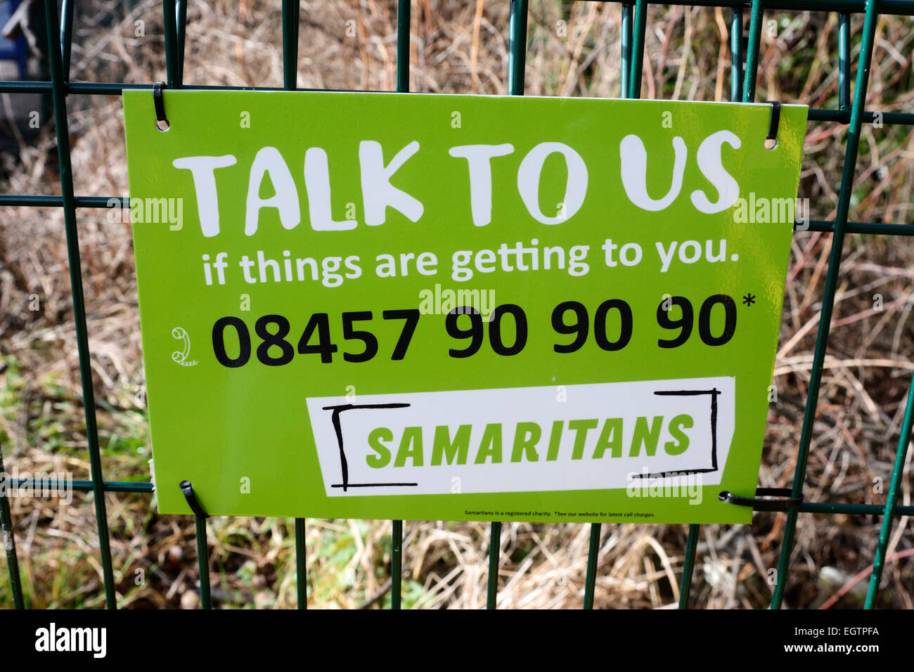 Samaritans sign attached to railings at a railway station covered with ...