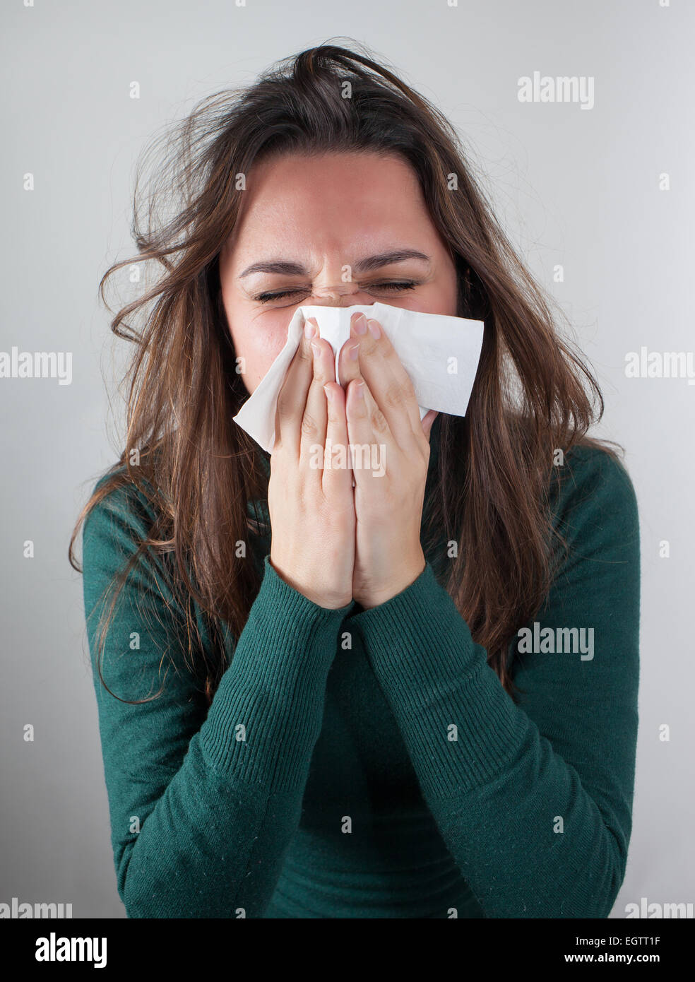 Young woman blowing her nose with paper tissue on gray background Stock ...