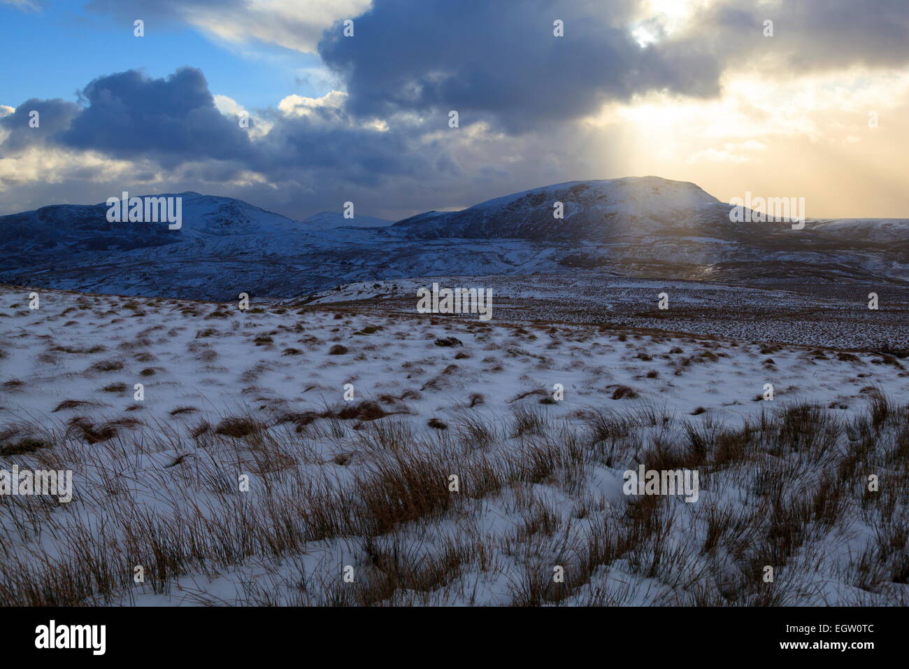 A low Winter Sun begins to set over Arenig Fach, Snowdonia. Arenig Fawr ...