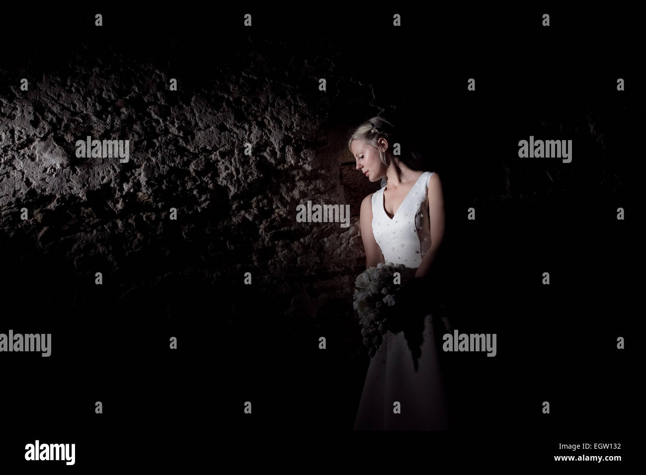 A portrait of a bride alone in the dark, spot-lit against a wall Stock ...