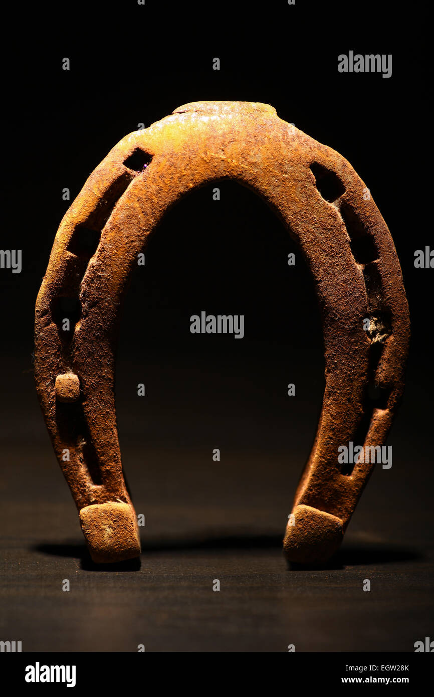 Color shot of a rusty horse shoe on a dark background Stock Photo - Alamy