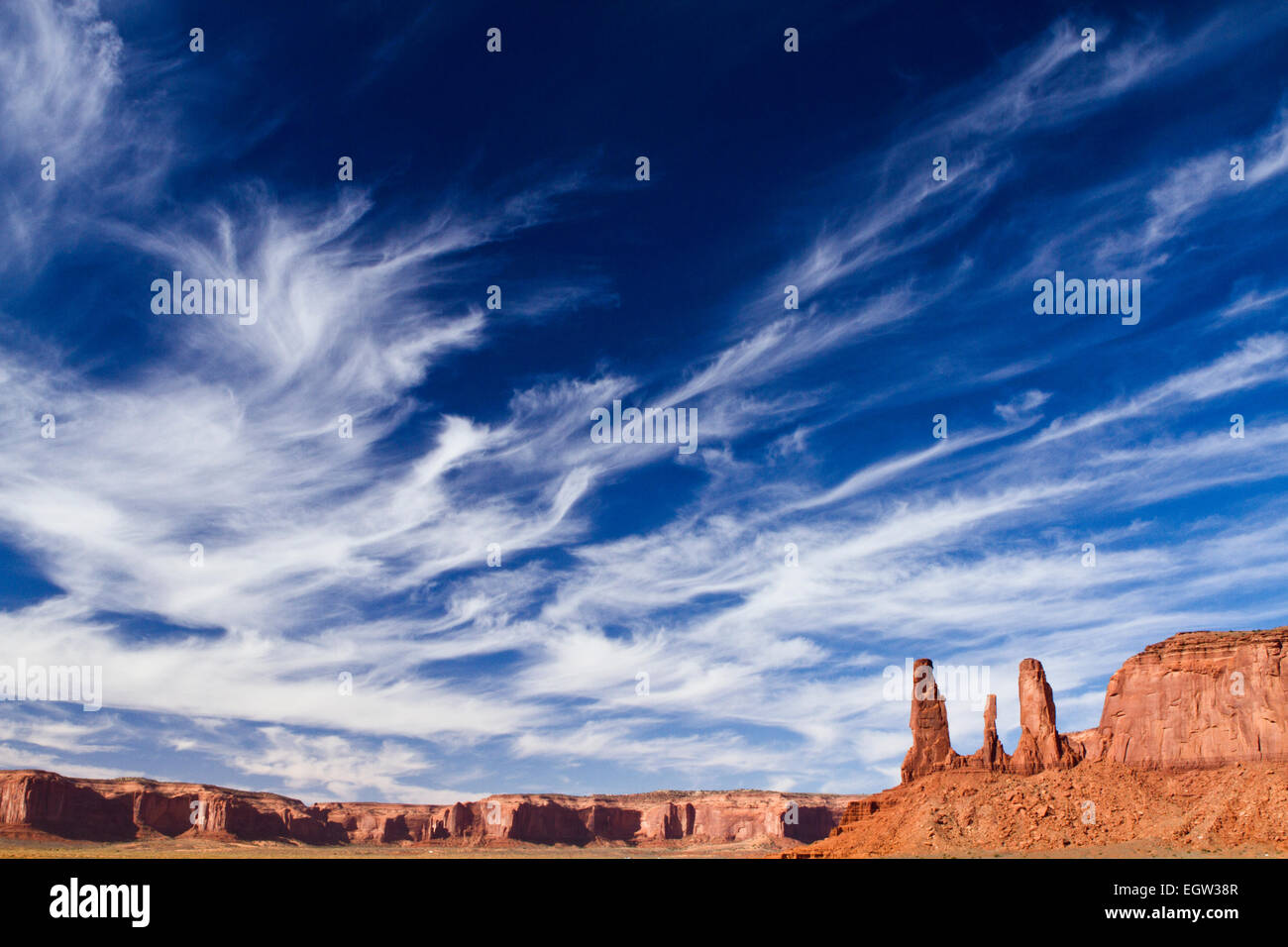 Wispy clouds over Three Sisters in Monument Valley, Utah Stock Photo ...