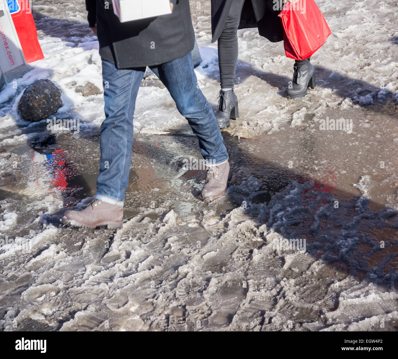 Pedestrians slog through puddles of slush and snow at street crossings ...