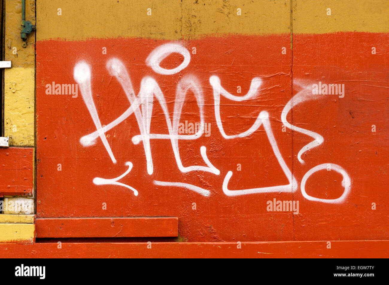 Graffiti tag on a colourful exterior wall and door of an old building ...