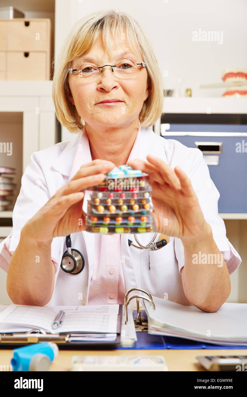 Old female doctor sitting with stack of many drugs in her office Stock ...