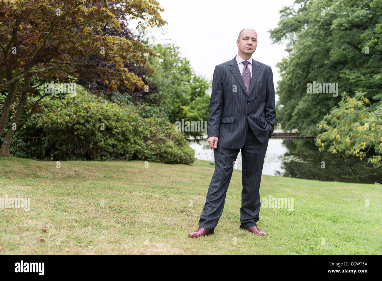 a professional businessman / hotel manager stands in the gardens of an ...