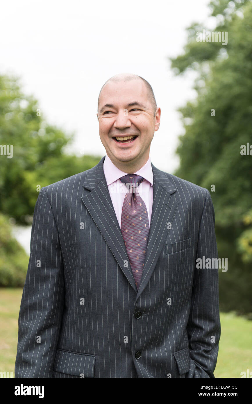 a professional businessman / hotel manager stands in the gardens of an ...