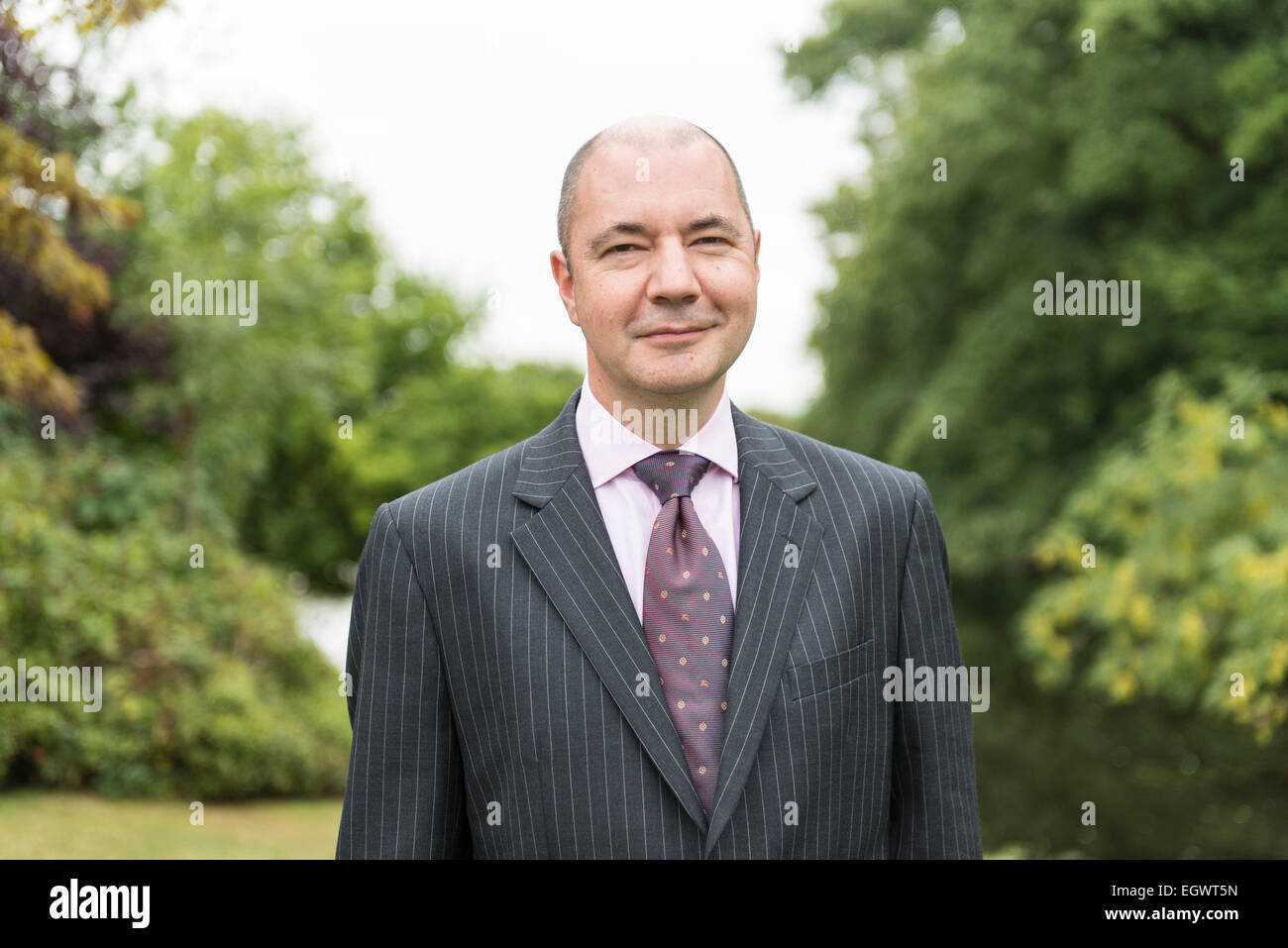 a professional businessman / hotel manager stands in the gardens of an ...