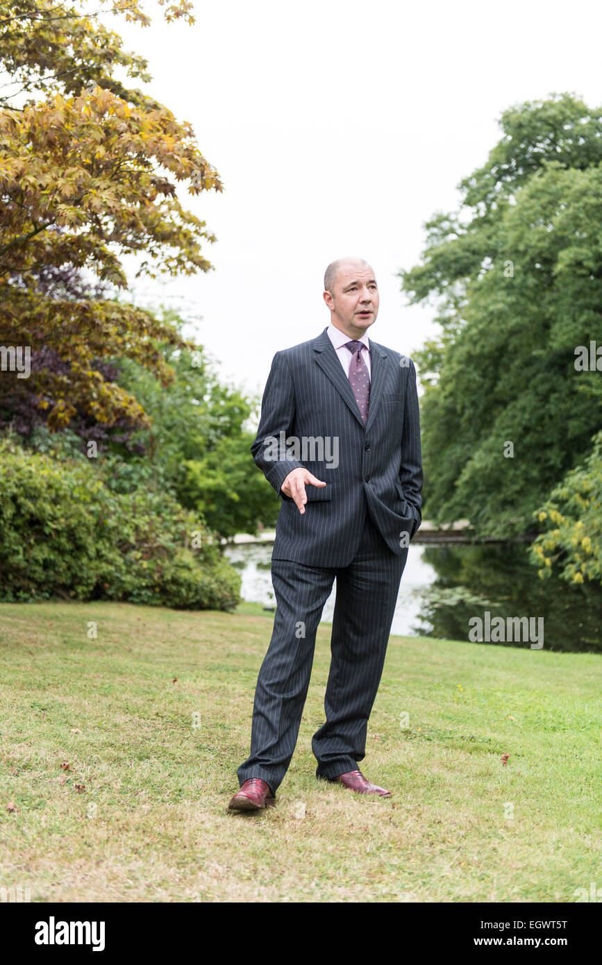 a professional businessman / hotel manager stands in the gardens of an ...