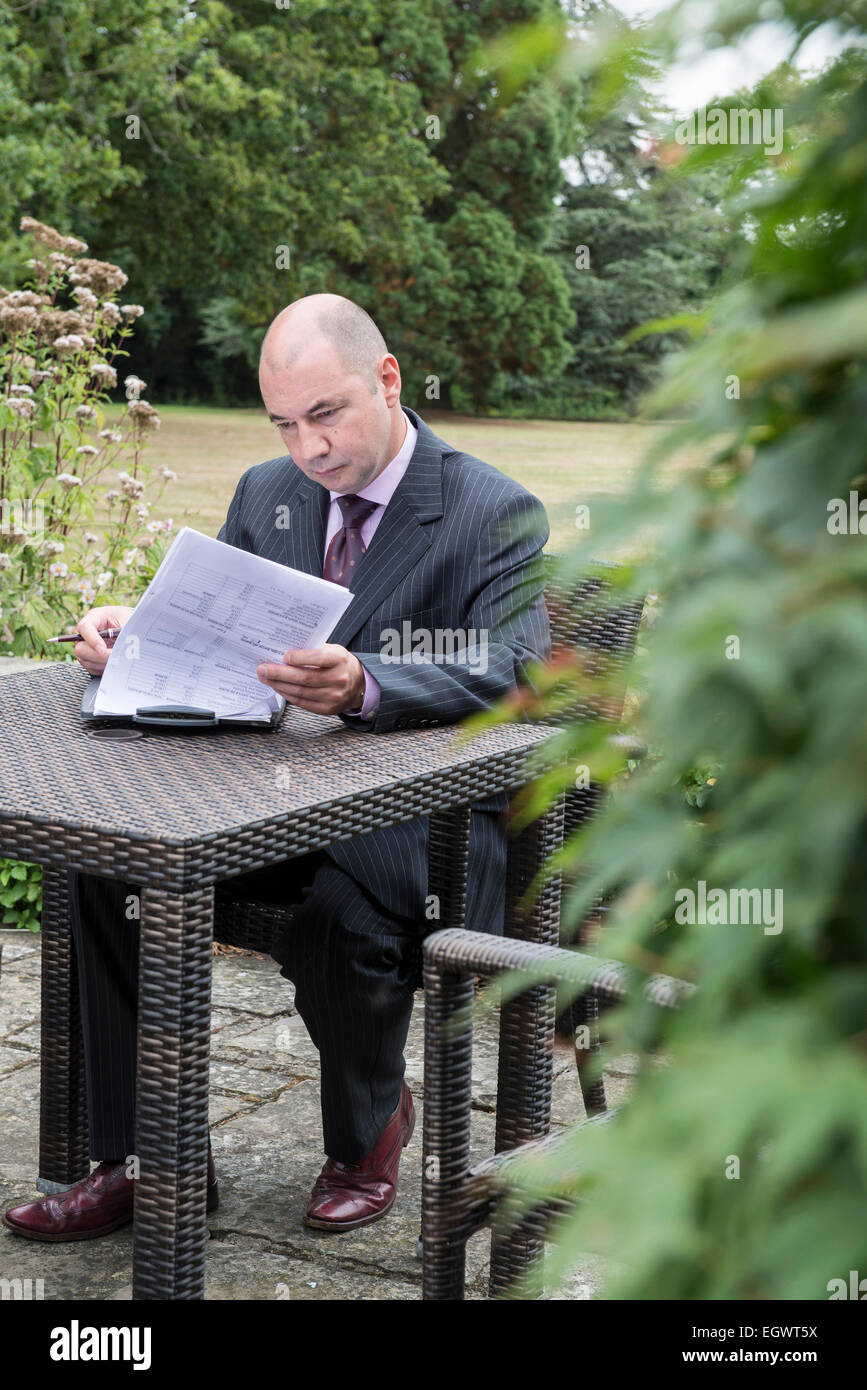 a relaxed professional businessman / manager sits at a table outside ...