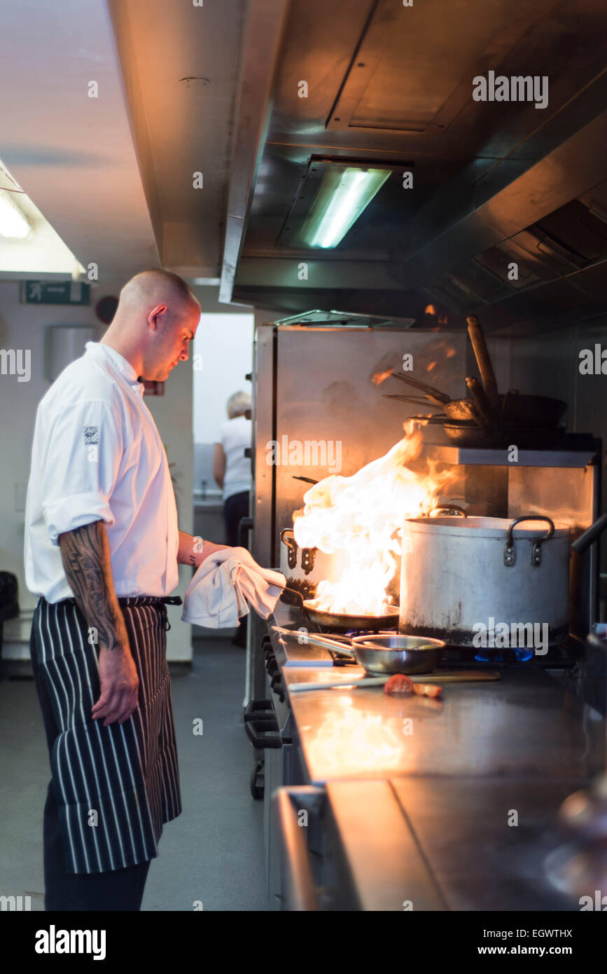 A professional mean ^ moody looking chef stands in his kitchen, looking ...