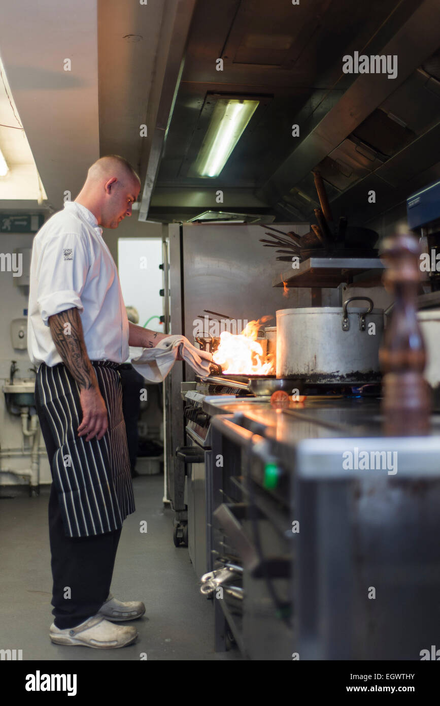 A professional mean ^ moody looking chef stands in his kitchen, looking ...