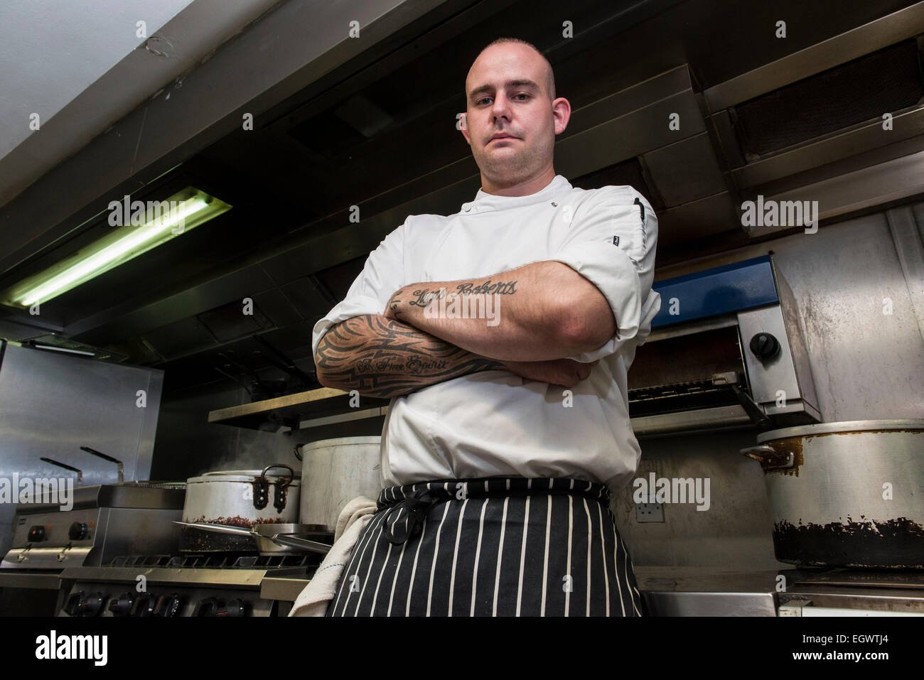 A professional mean ^ moody looking chef stands in his kitchen, looking ...