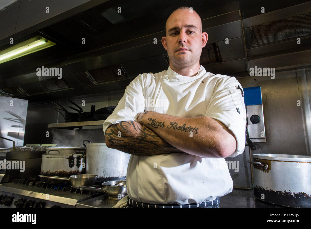 A professional mean ^ moody looking chef stands in his kitchen, looking ...