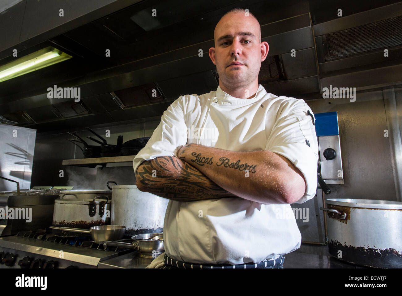 A professional mean ^ moody looking chef stands in his kitchen, looking ...