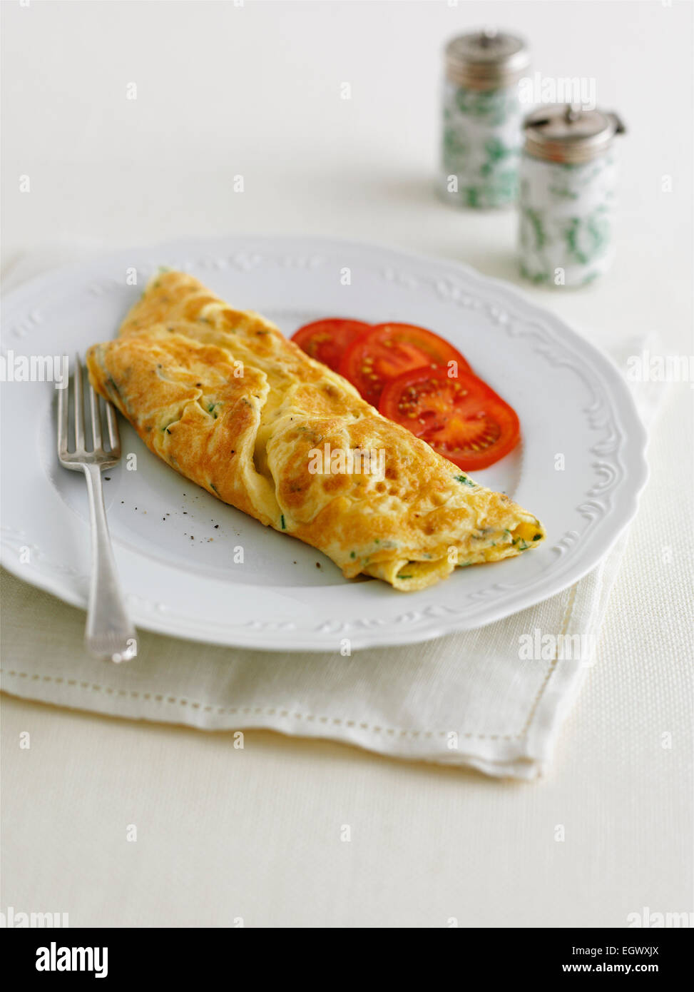 Classic French herbed omelette garnished with tomato slices, on plate ...