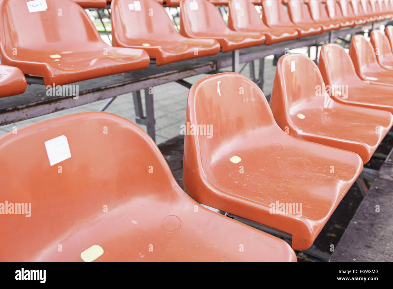 Chairs stacked wood detail of chair in a football field, spectators and ...