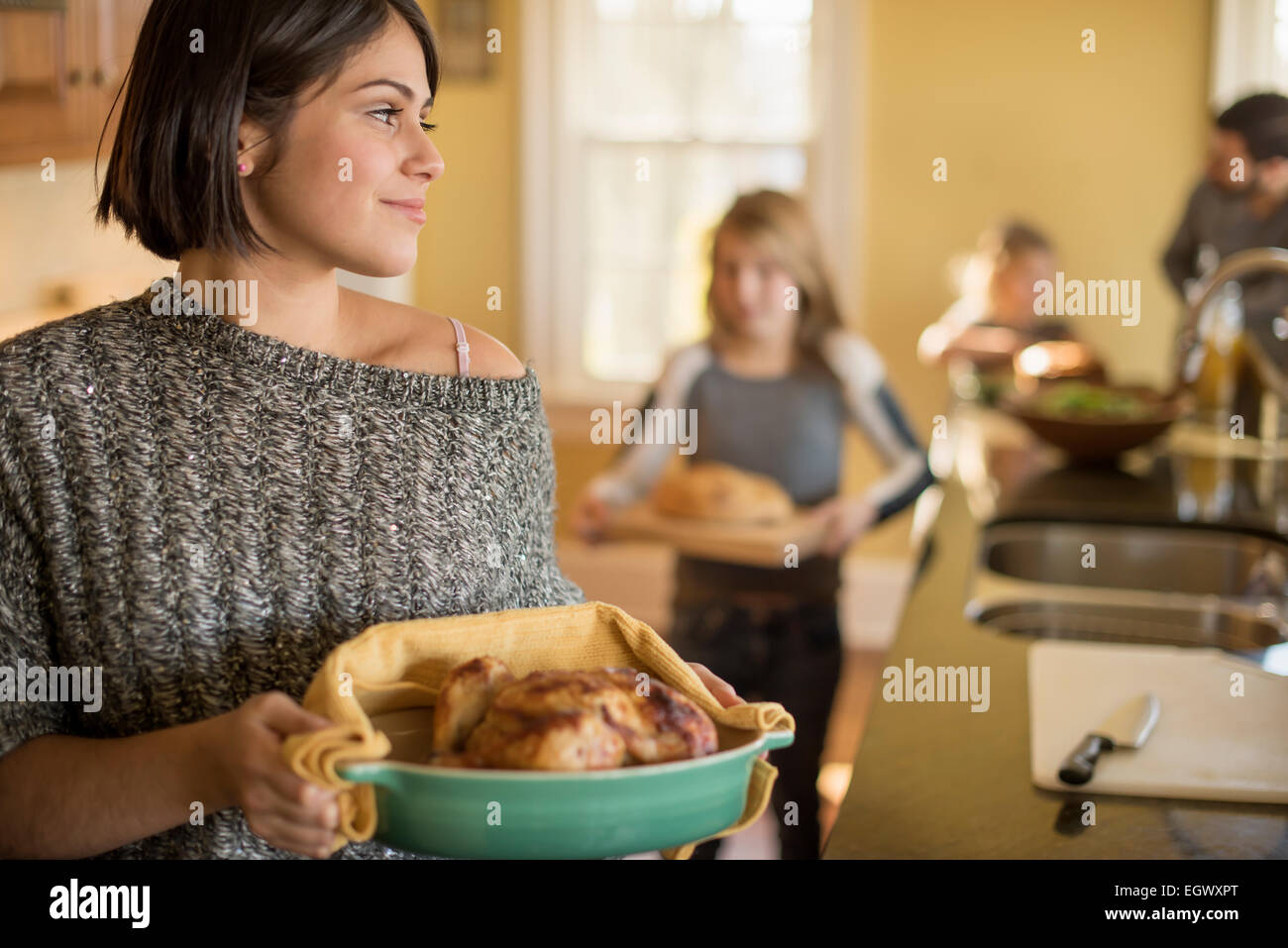 A woman and two girls carrying food to a table Stock Photo - Alamy