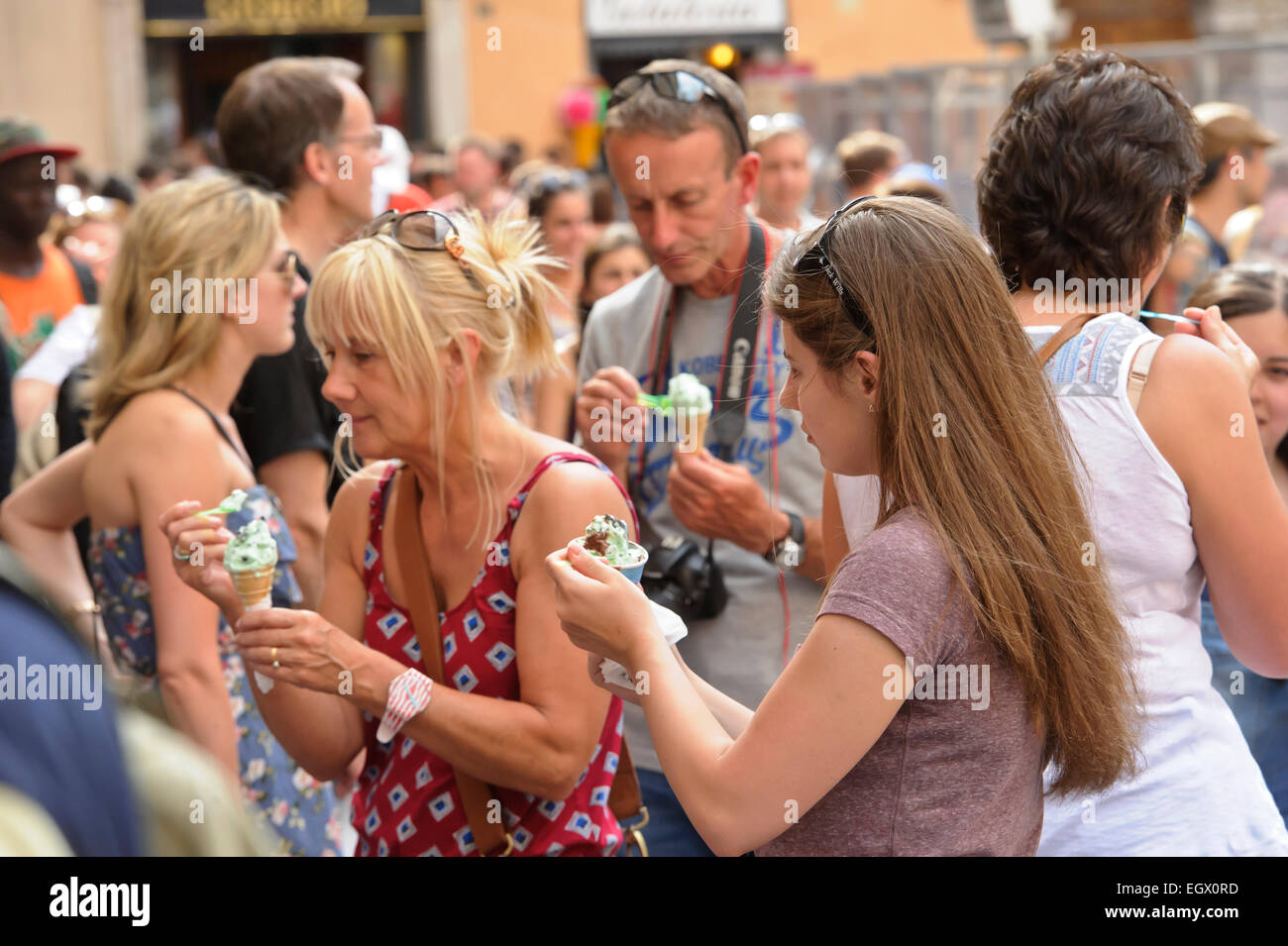 A family eating ice cream among the crowd on the street, Rome, Italy ...