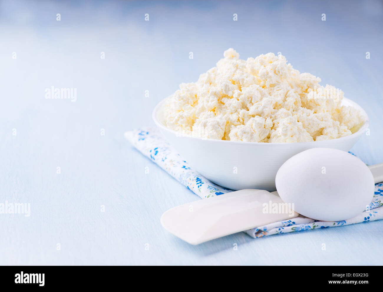 Cottage cheese in white bowl over light blue background, selective ...