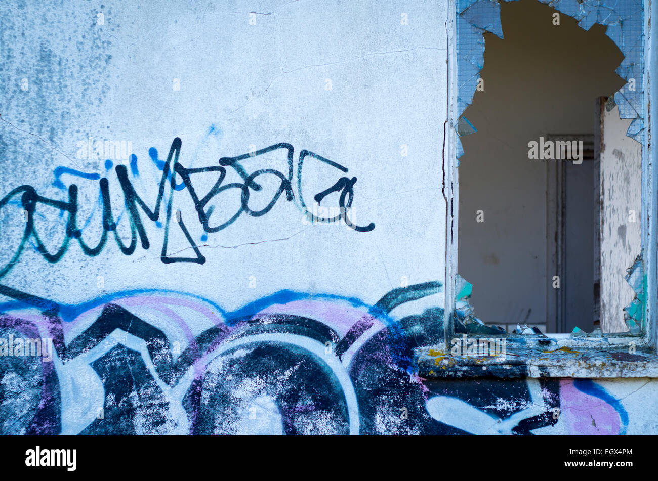 Graffiti covered wall and broken window of vandalised derelict building ...