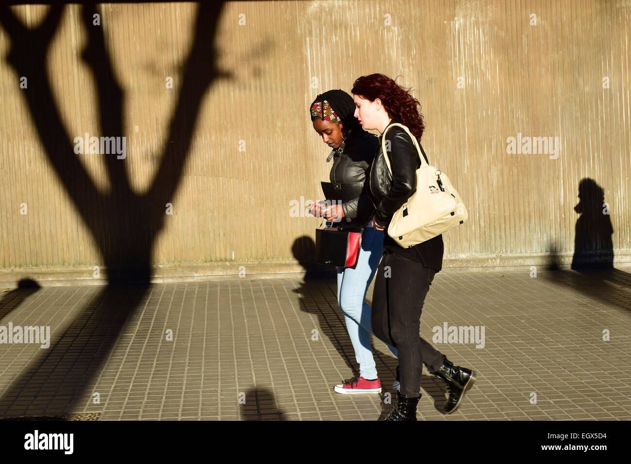 Two young women walking along a wall Stock Photo - Alamy