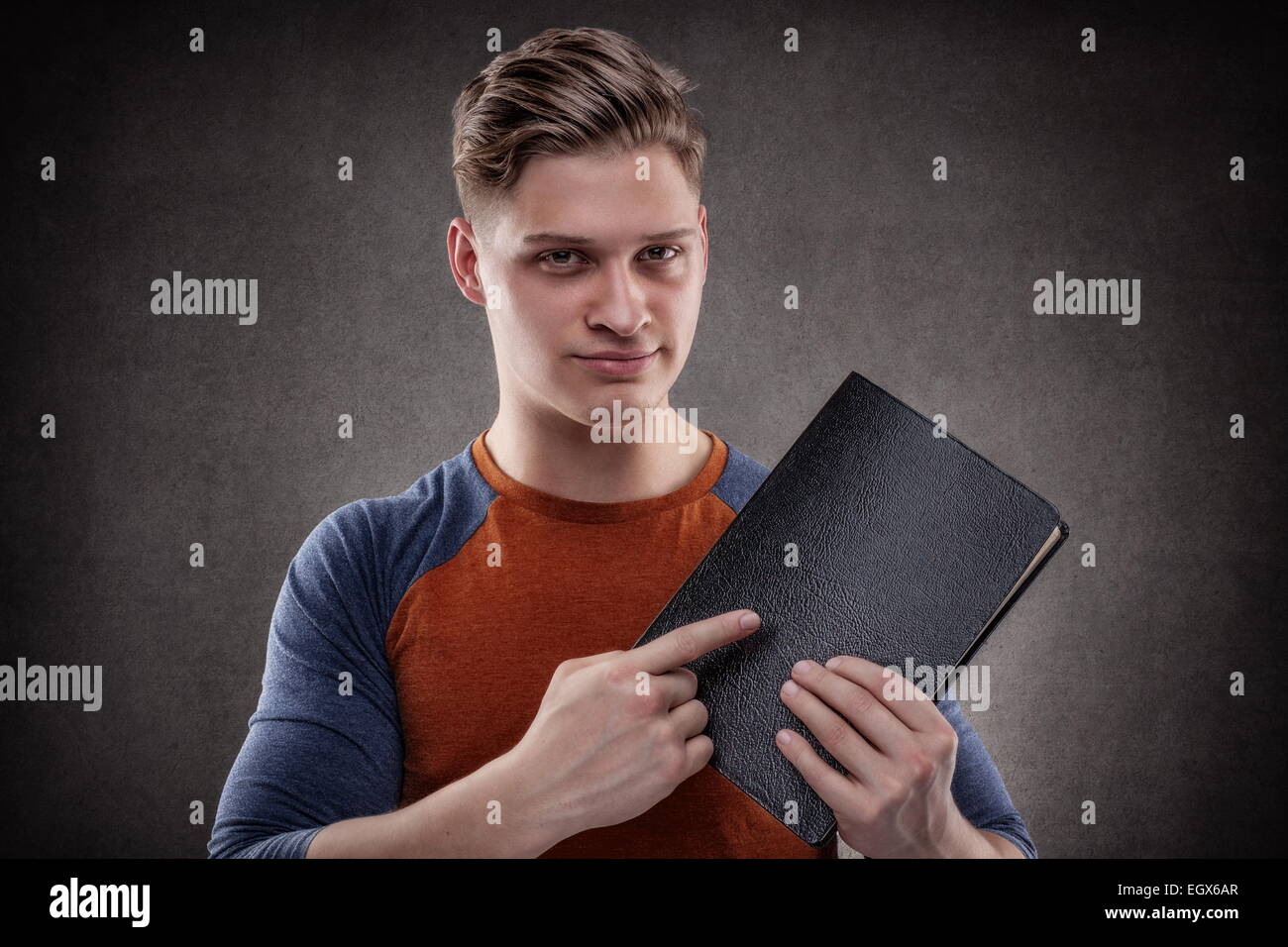 Happy young man pointing a big book with leather covers Stock Photo - Alamy