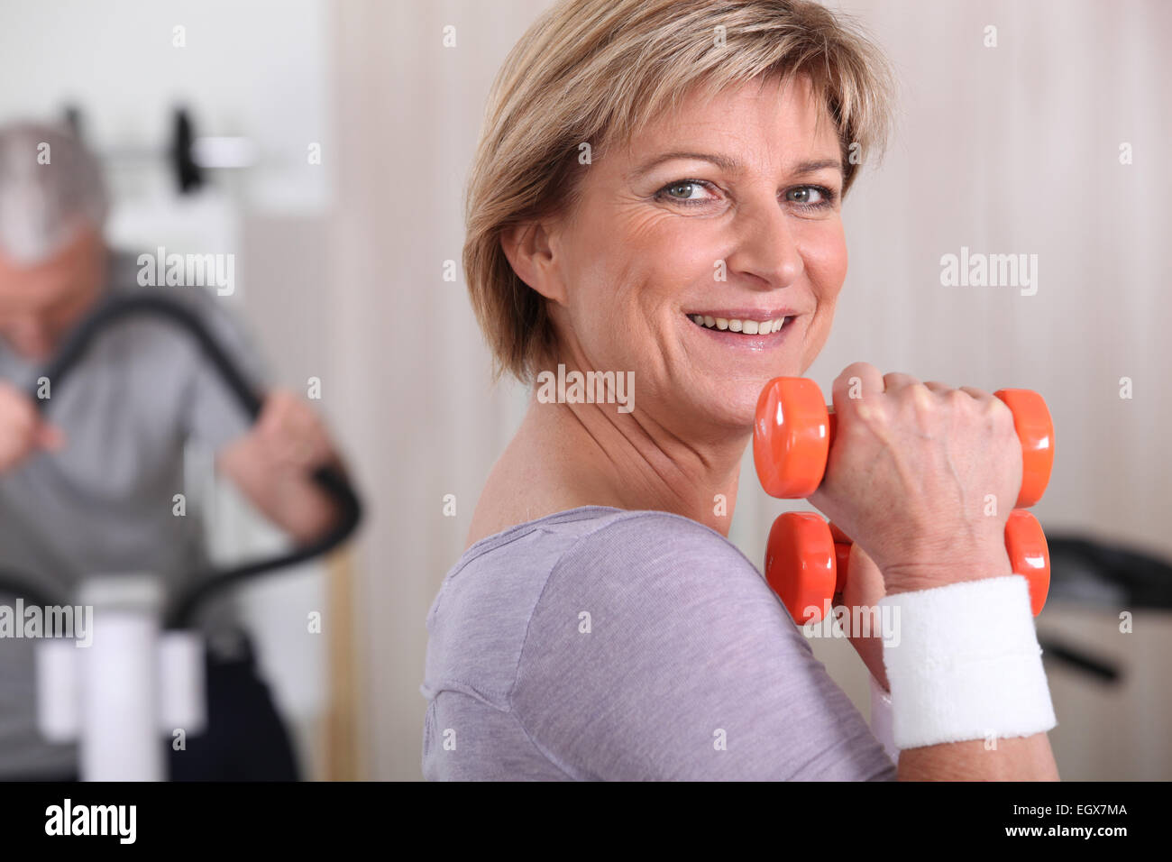 Woman using dumbbells in a gym Stock Photo - Alamy