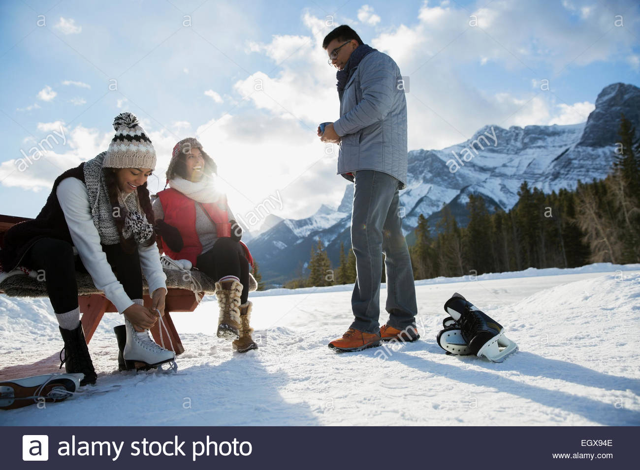 Family putting on ice skates below snowy mountain Stock Photo - Alamy