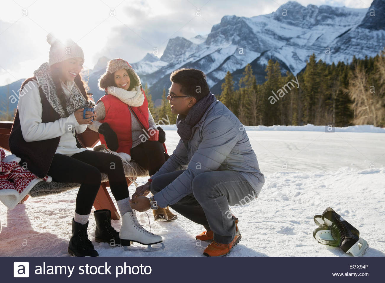 Family putting on ice skates below snowy mountain Stock Photo - Alamy