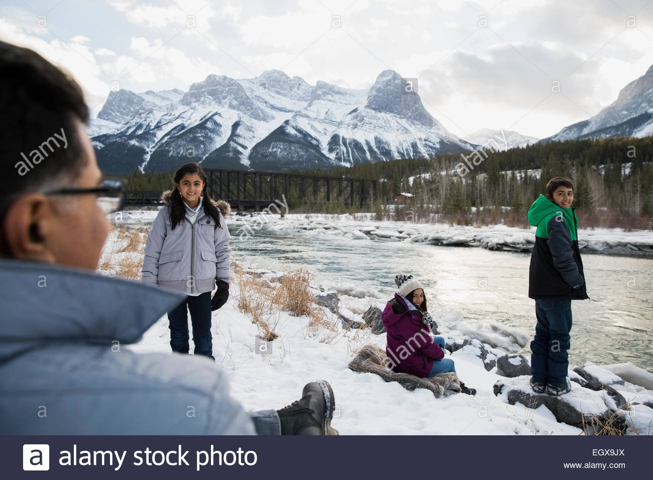 Family playing at riverside below snowy mountains Stock Photo - Alamy
