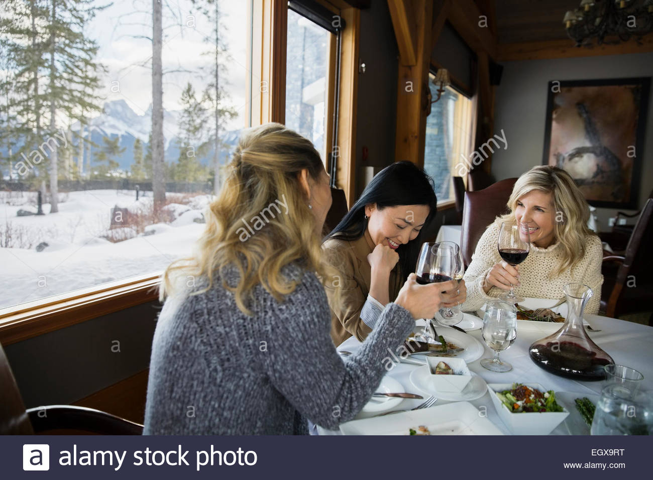 Women laughing and drinking wine at restaurant table Stock Photo - Alamy