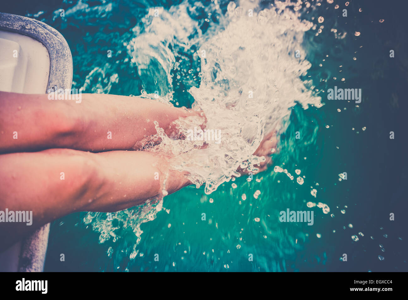Female legs splashing sea water from a sailing yacht. Filtered shot ...