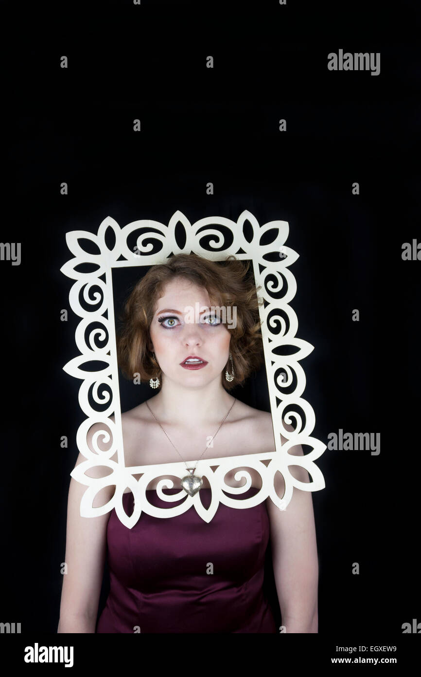 Beautiful woman with white wooden frame on her head on black background ...
