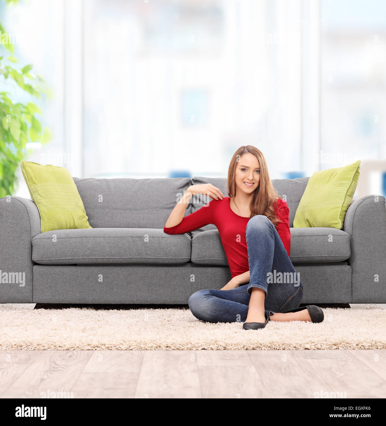 Relaxed young woman sitting by a sofa at home shot with tilt and shift ...
