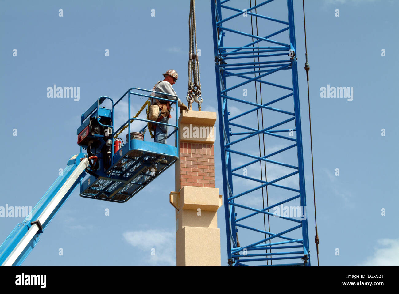 A construction worker guides a piece of architectural precast concrete ...