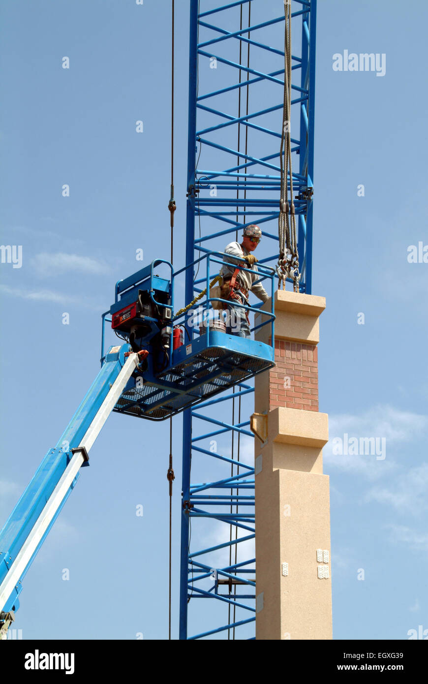 A construction worker guides a piece of architectural precast concrete ...