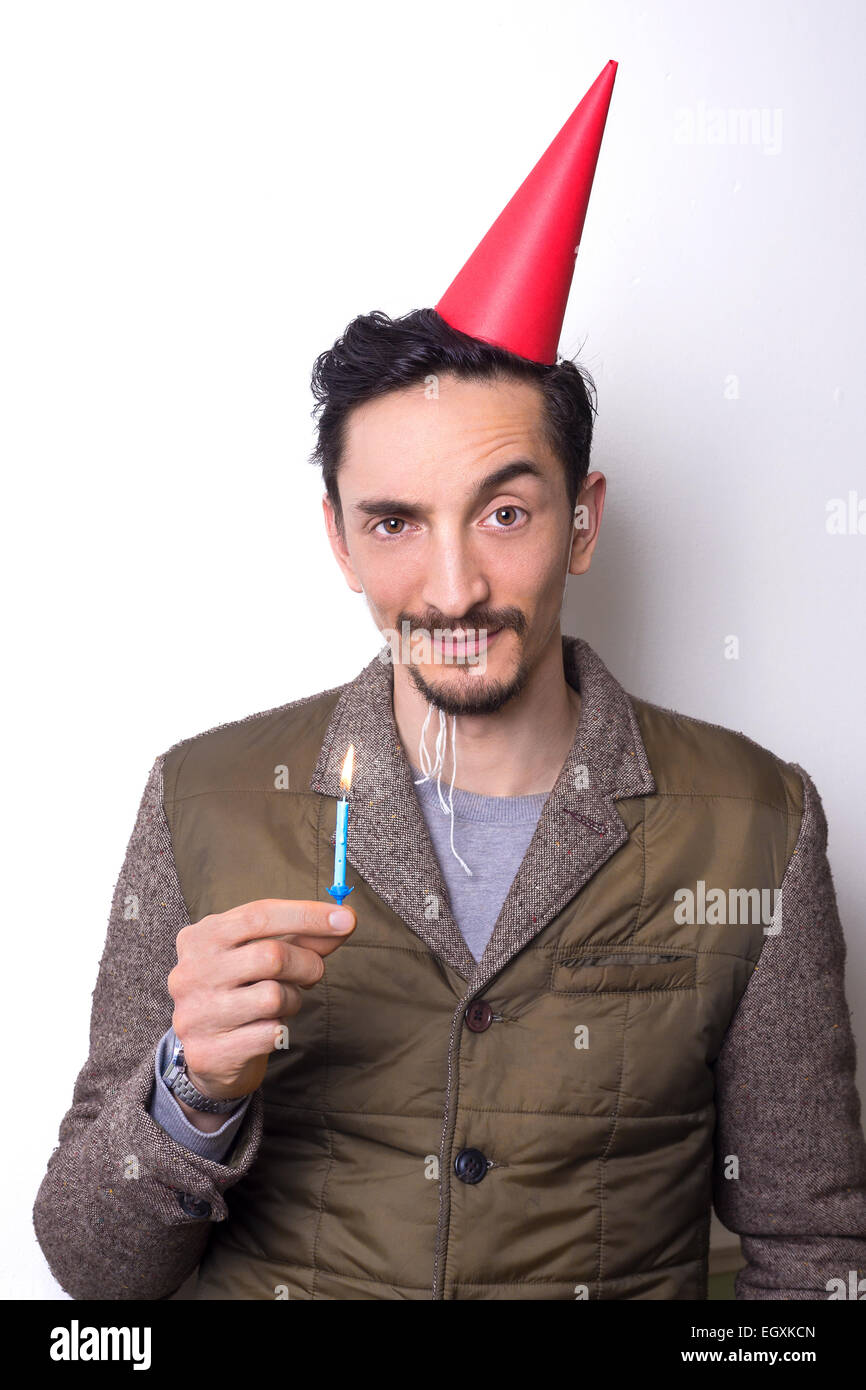man in his thirties holding a birthday candle and looking dubious Stock ...