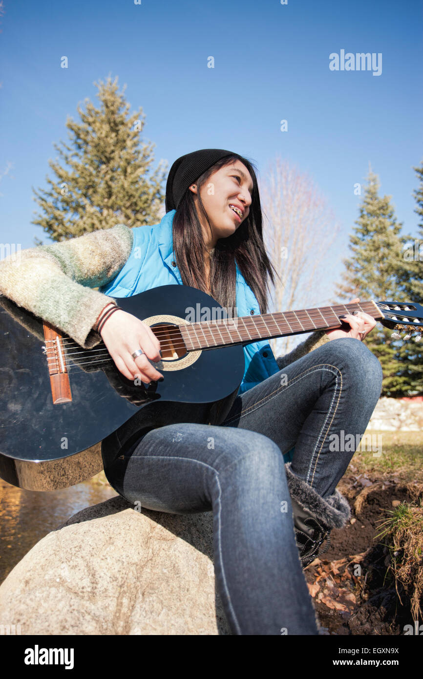 Sitting on a rock playing guitar Stock Photo - Alamy