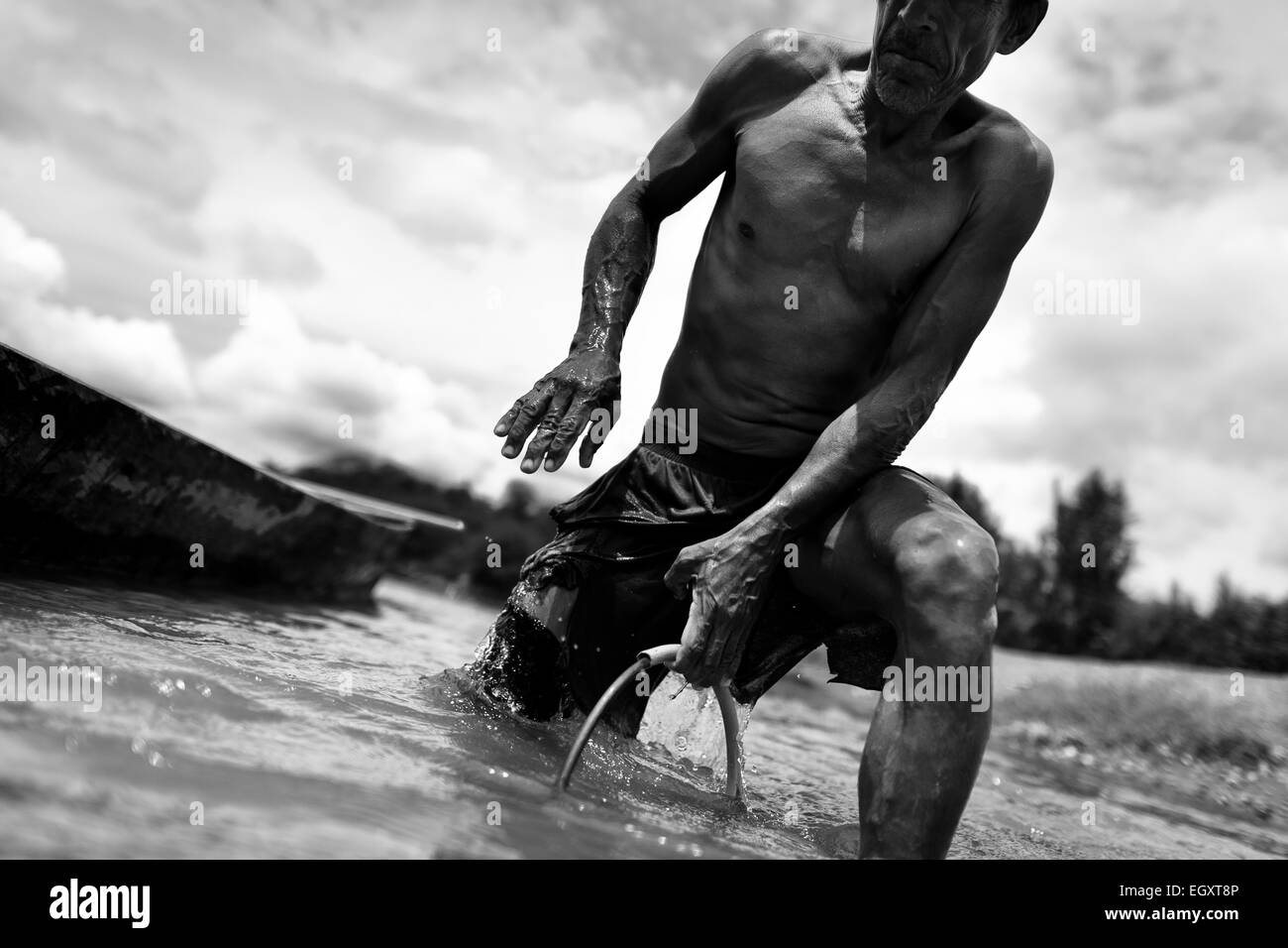 A Colombian sand miner lifts up a bucket full of sand while working in ...