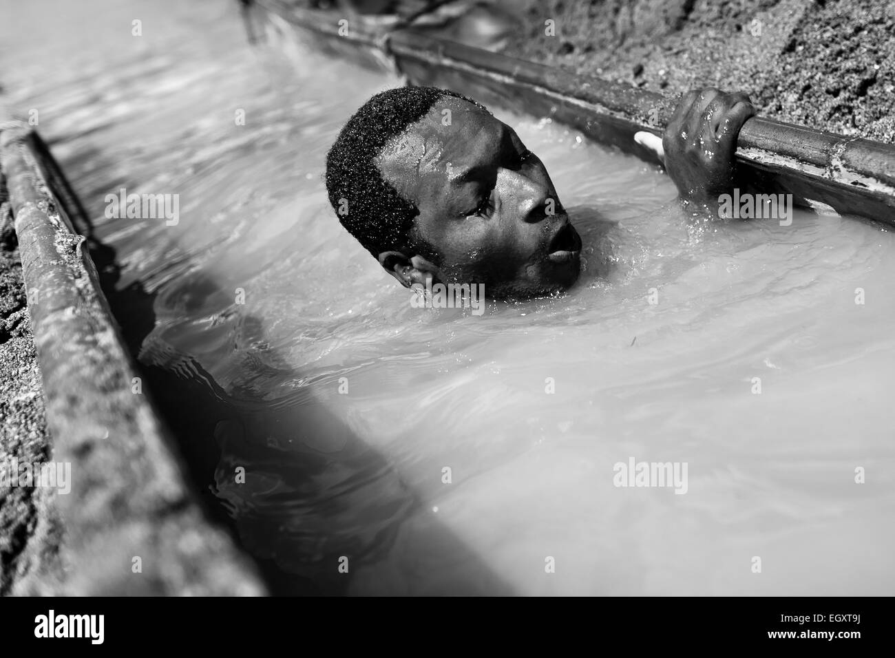 A Colombian sand miner dives under the water to extract sand from the ...