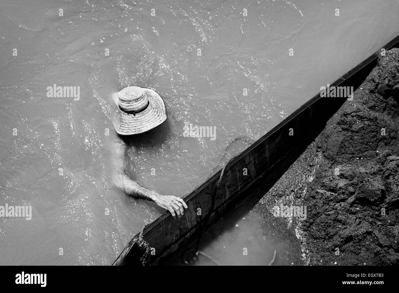 A Colombian sand miner dives under the water to extract sand from the ...