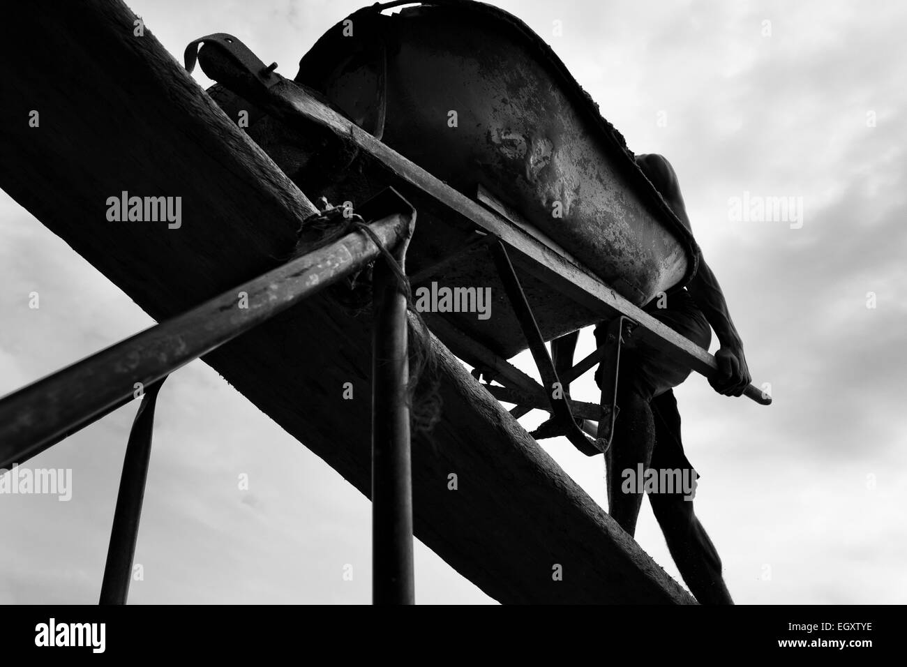 A Colombian sand miner, using a wheelbarrow, unloads sand from the boat ...